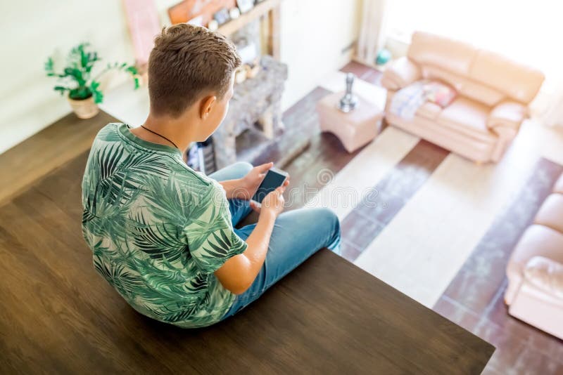 The Teenager is Using Cell Phone, Sitting on the Second Floor of the ...