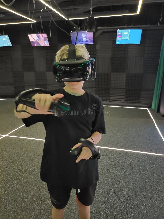 A Teenager in VR Glasses with Augmented Reality and with Controllers in ...