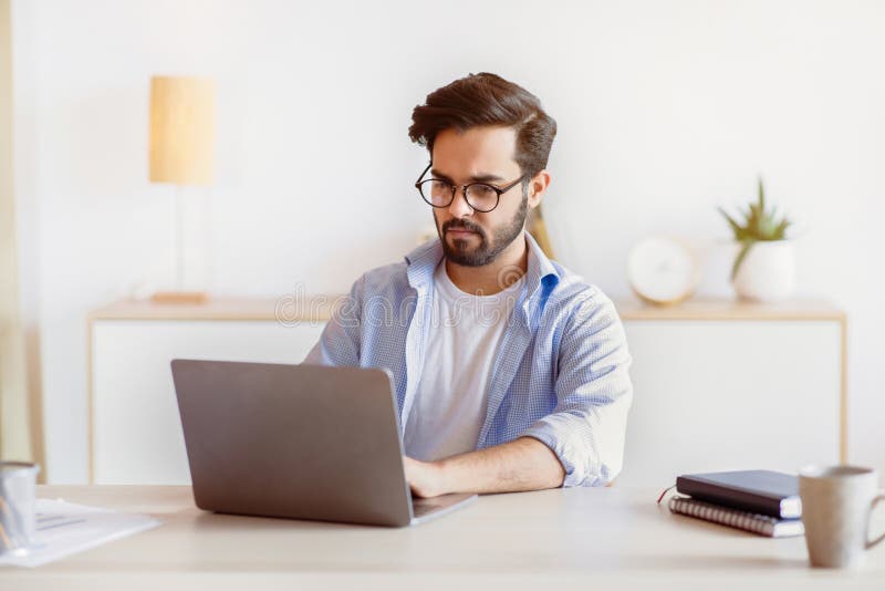 Telecommuting. Eastern Man Using Laptop Computer, Sitting at Desk in Home Office Stock Image ...