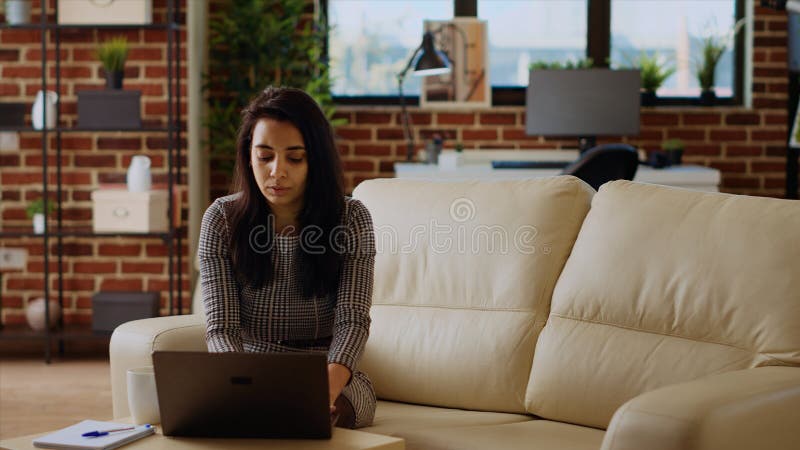 Teleworker Sitting on Couch, Focused on Finishing Tasks in Personal ...