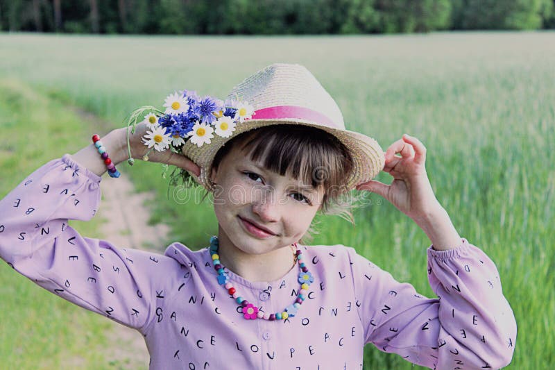 A Ten Year Old Girl Holds A Hat On Her Head And A Bouquet Of Wild