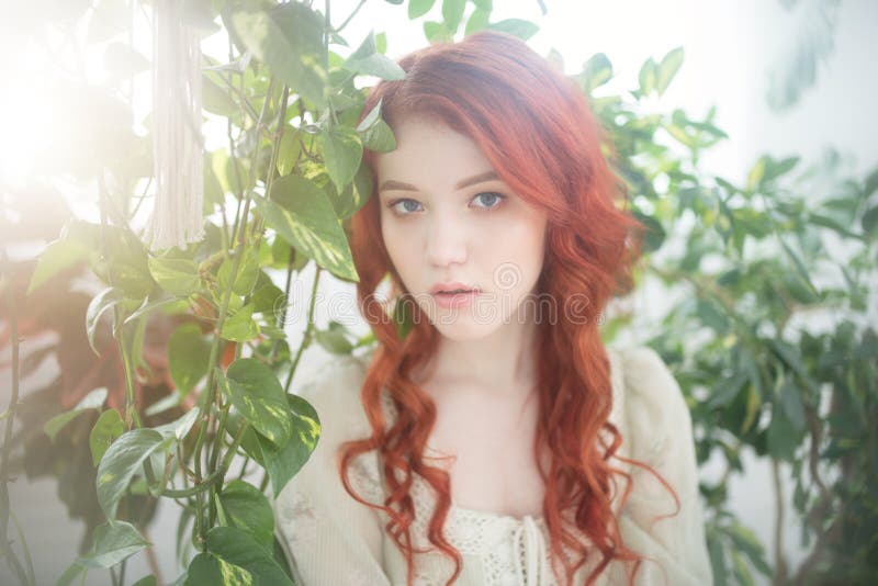 Tender Portrait Of A Young Beautiful Dreamy Redhead Woman Among Foliage