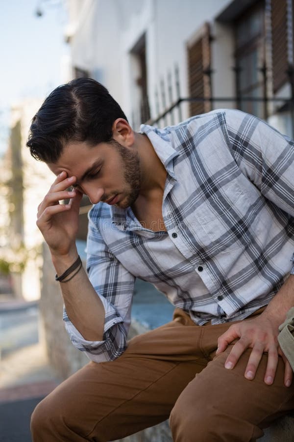 Tensed Young Man with Head in Hands Sitting on Retaining Wall Stock ...