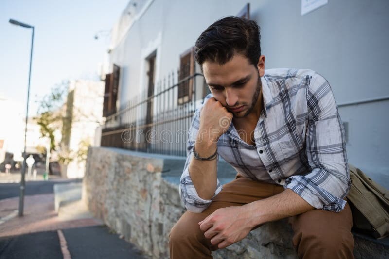 Tensed Man Looking Down while Sitting on Retaining Wall Stock Photo ...