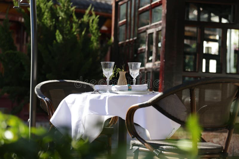 Terrace Restaurant Setting with Table and Chairs Surrounded by Green ...