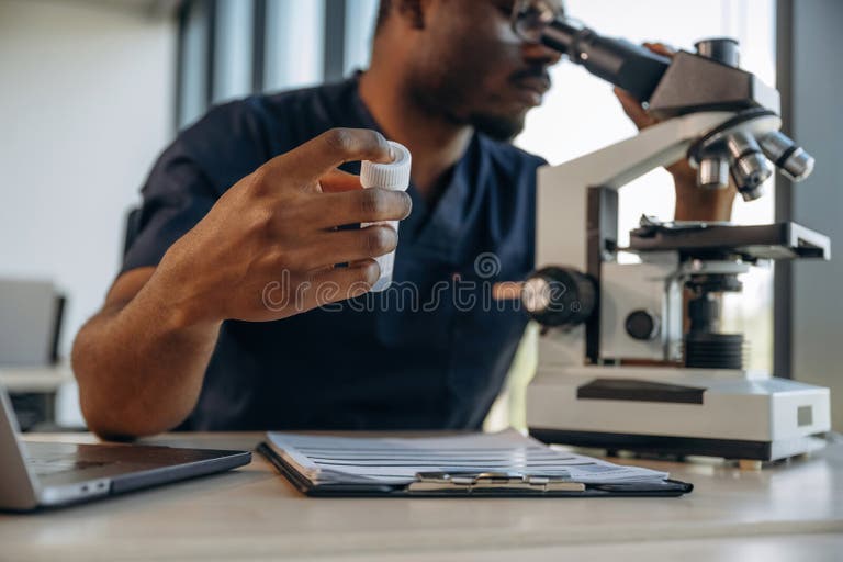 Test Tube in Hand, Using the Microscope. Scientist is Working Indoors ...