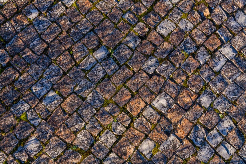 A Textured Cobblestone Road Surface, with Tufts of Grass Growing ...