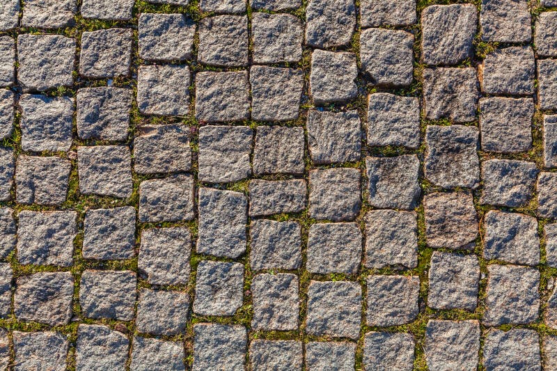 A Textured Cobblestone Road Surface, with Tufts of Grass Growing ...
