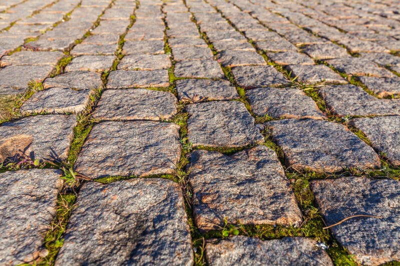 A Textured Cobblestone Road Surface, with Tufts of Grass Growing ...
