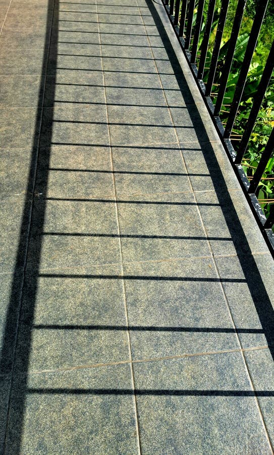 Textured Outdoor Tile Walkway with Shadows from a Railing. Stock Image ...