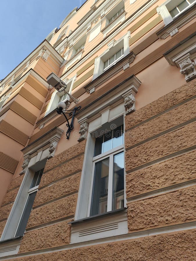 Textured Peach Building Facade with Ornate White Window Frames and a ...