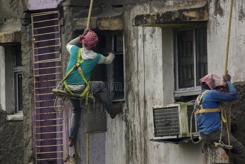 Two Construction Workers Doing Repair Work of Outer Wall while Hanging ...