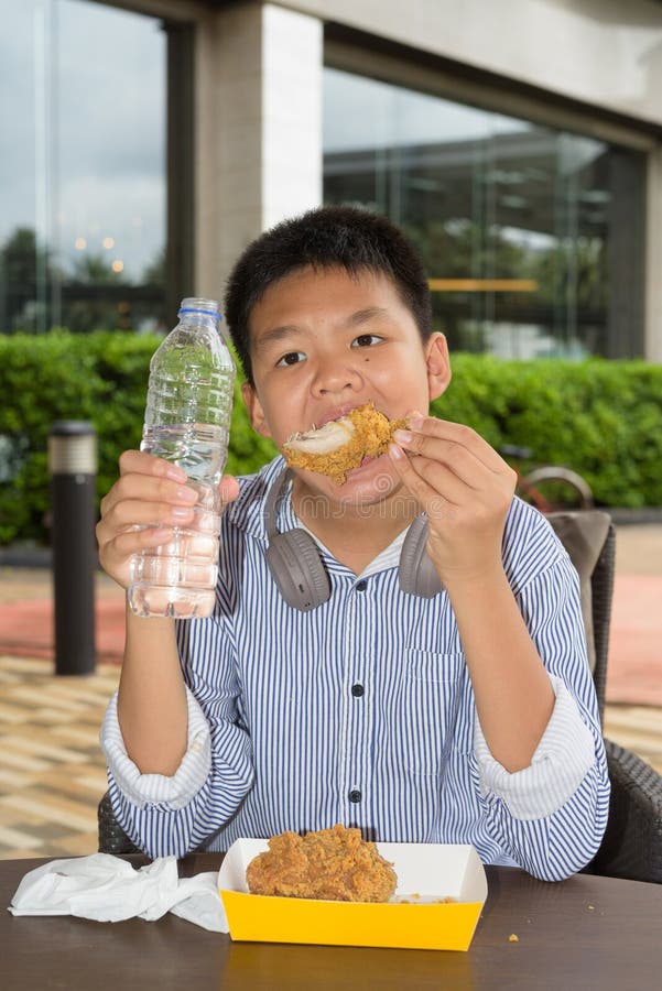 Thai Boy Eating Fried Chicken and Drinking Water Outdoors Stock Photo ...