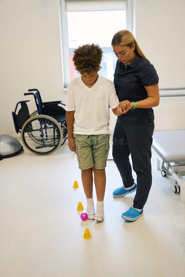 Therapist Assists a Young Patient in Performing a Balance Exercise ...