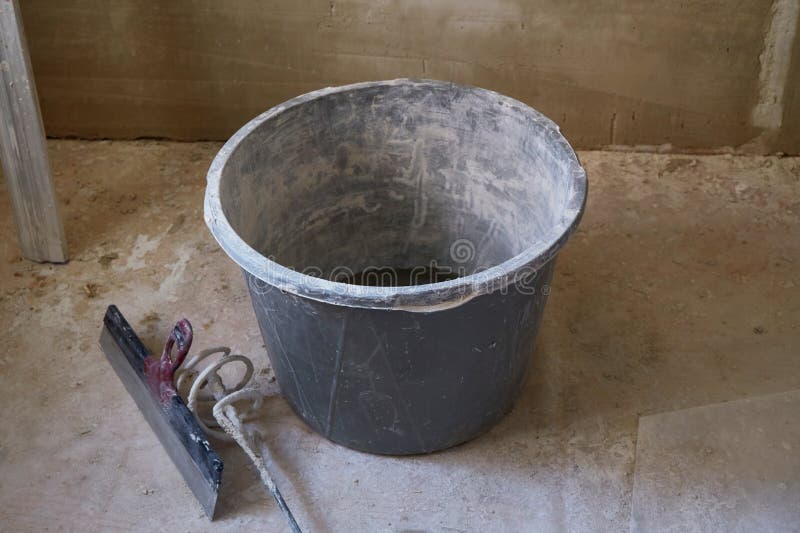 There is a Bucket and a Plaster Spatula on the Construction Site ...