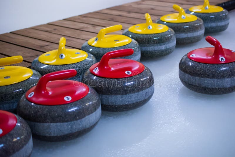 There are Curling Stones with Red and Yellow Handles on the Ice. the ...
