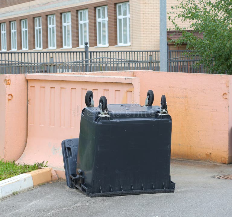 There is an Inverted Black Plastic Container by the Pink Wall of the ...