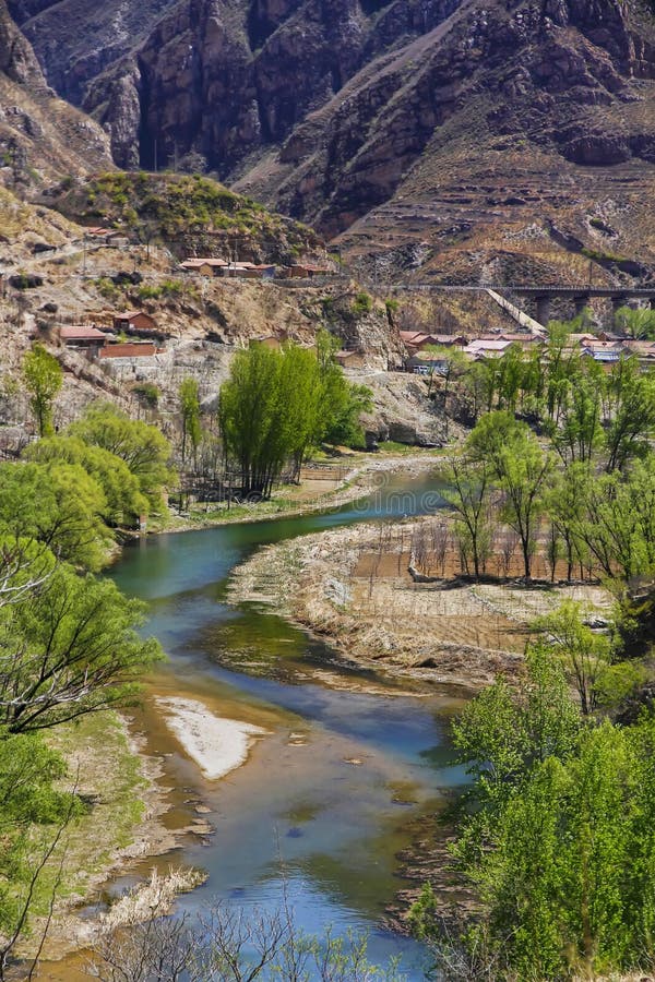 There is a Long River at the Foot of the Mountain with Green Trees on ...