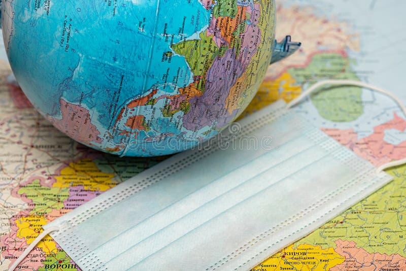 There is a Round Globe on the Paper Map of the World. a Protective Mask ...