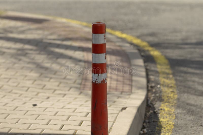 There is a Red and White Colored Pole Located on the Roadside Area ...