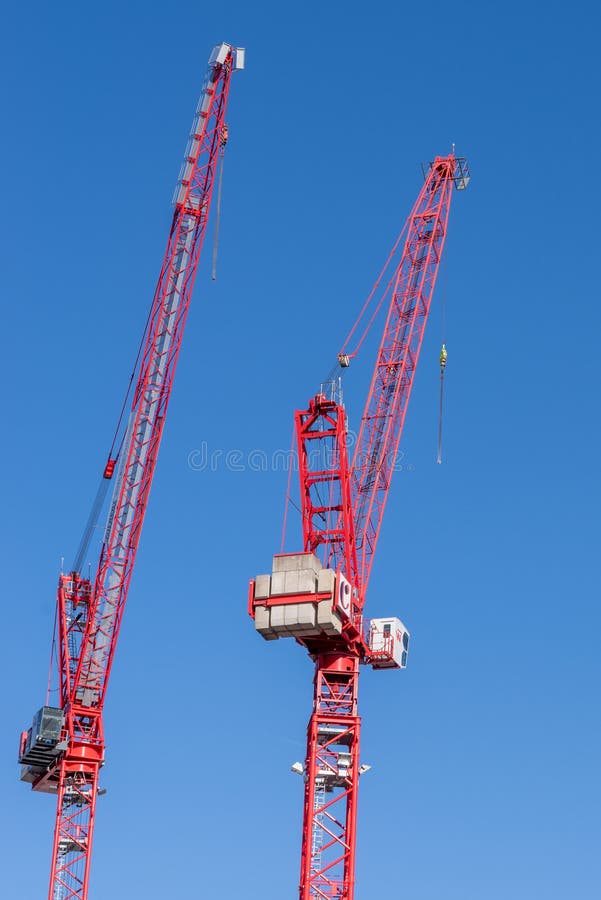 There are Two Tall Red Construction Cranes Set Against a Bright Blue ...
