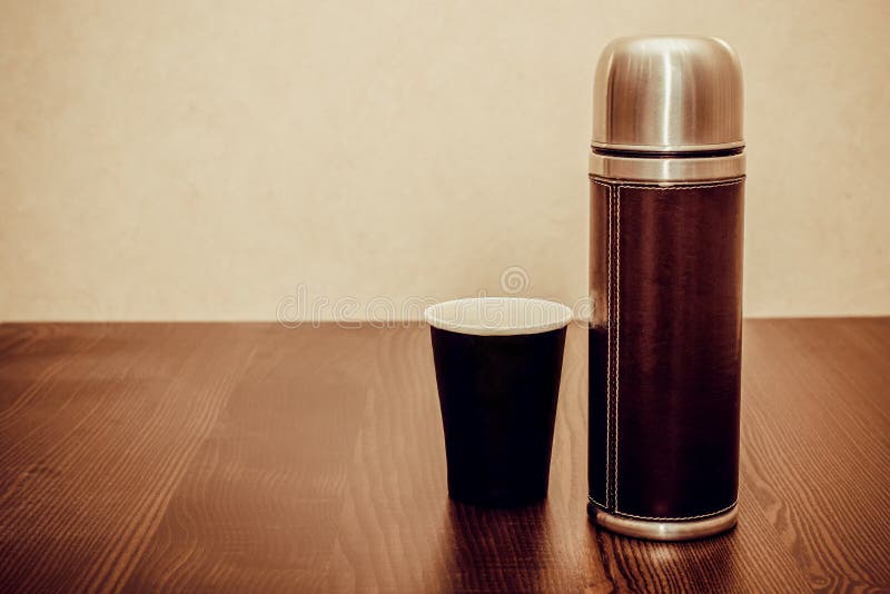 A Thermos and a Paper Cup of Coffee are on the Table. Space for Text or ...