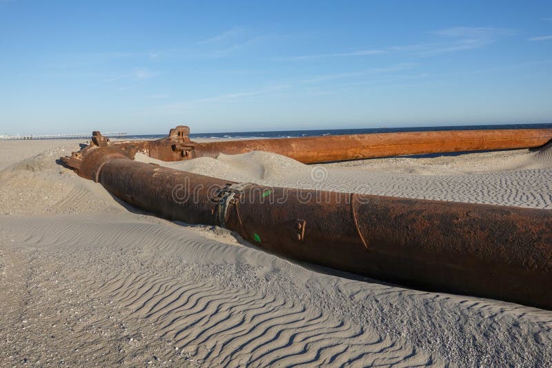 A Thick Rusty Pipeline Making a Right Angle Turn on a Sandy Beach Near ...