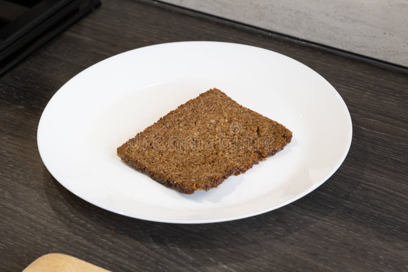 A Thick Slice of Dark Rye Bread Rests on a White Plate Stock Image ...