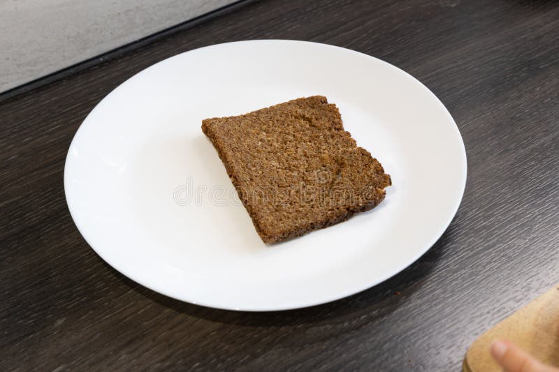 A Thick Slice of Dark Rye Bread Rests on a White Plate Stock Photo ...