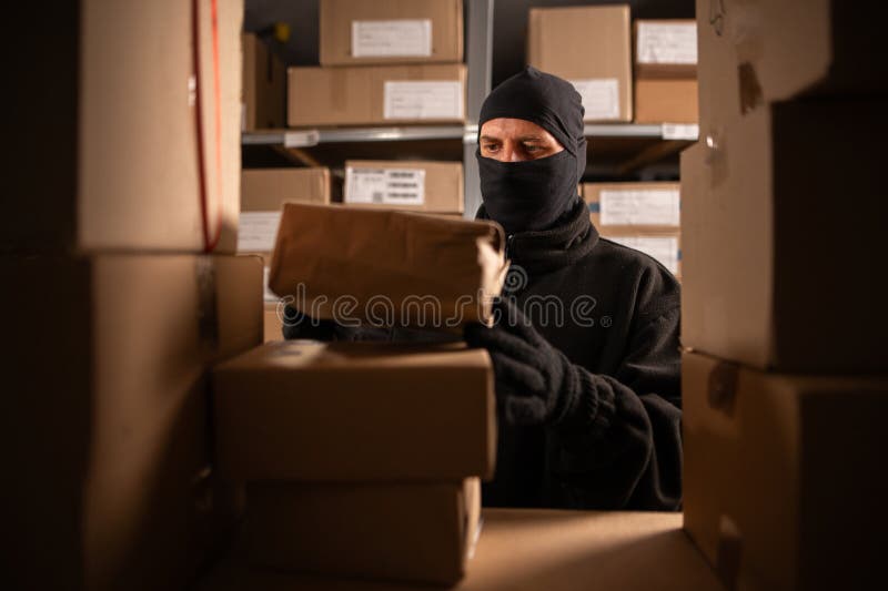 A Night Thief in a Black Mask Steals Boxes of Goods in a Warehouse ...