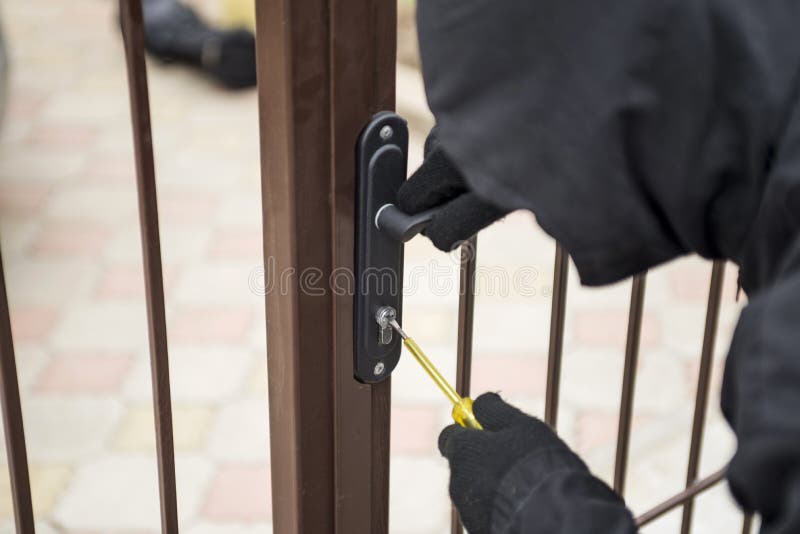 Thief Breaking Lock To Open the Gate. Male Thief Trying To Open Gate ...