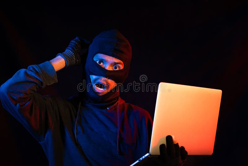 The Thief Holds the Computer on a Black Background,Wondering Face Stock ...