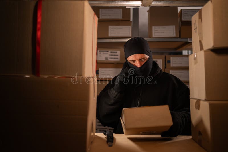 Thief Stealing a Box in a Warehouse Calls on a Mobile Phone at Night ...