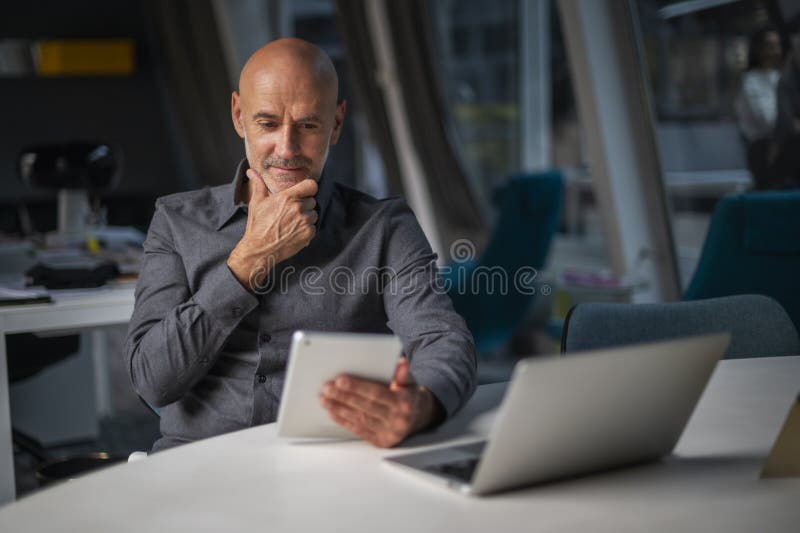 Thinking Middle Aged Businessman Using Digital Tablet and Laptop for ...