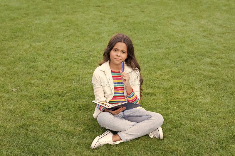 Thinking Teen Girl Making Notes in Notebook Sitting on Grass. Taking ...