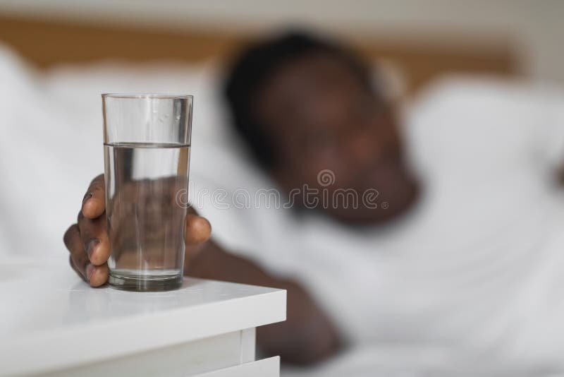 Thirsty Black Man Taking Glass of Water from Bedside Table in Bedroom ... Thirsty Black Man Taking Glass of Water from Bedside Table in Bedroom ...