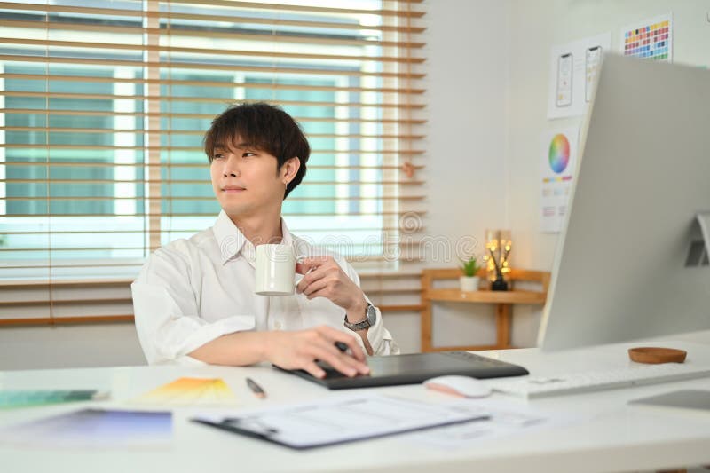 Thoughtful Asian Man Web Developer Drinking Coffee and Looking through ...