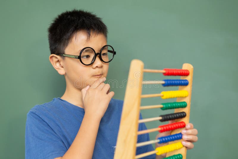 Thoughtful Boy Learning Math with Abacus Against Green Chalkboard in a ...
