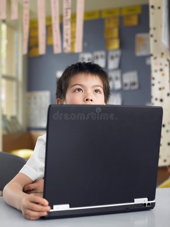 Thoughtful Boy Sitting by Laptop in Classroom Stock Photo - Image of ...