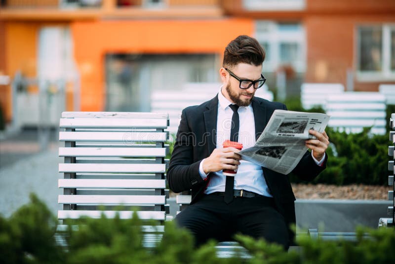 Thoughtful Businessman with Newspaper and Coffee Cup Sitting on Bench ... Thoughtful Businessman with Newspaper and Coffee Cup Sitting on Bench ...