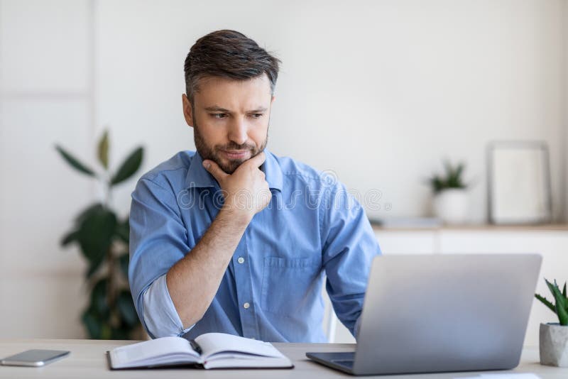 Thoughtful Businessman Working with Computer in Office, Looking at ...