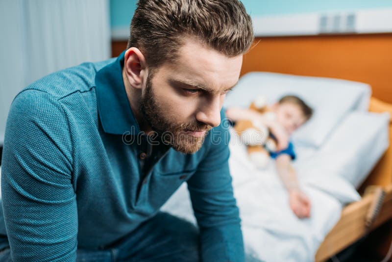 Thoughtful Dad Sitting Near Sick Son in Hospital Bed Stock Photo ...
