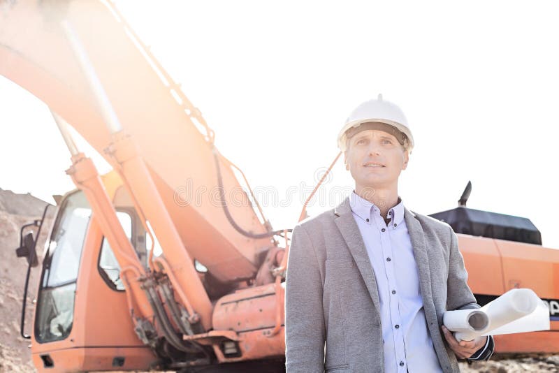 Thoughtful Engineer Looking Away while Holding Blueprints by Bulldozer ...