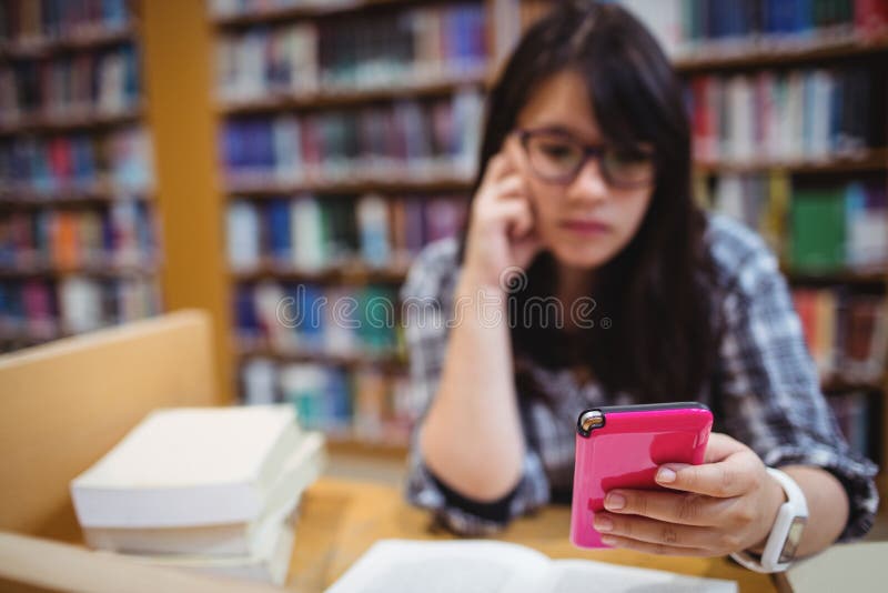 Thoughtful Female Student Using a Mobile Phone Stock Photo - Image of ...
