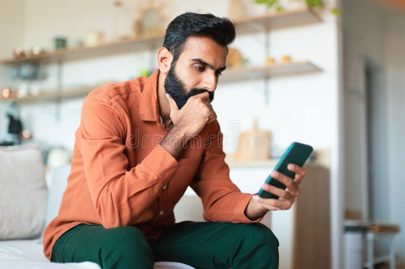 Thoughtful Indian Man Holding Smartphone Texting and Thinking at Home ...