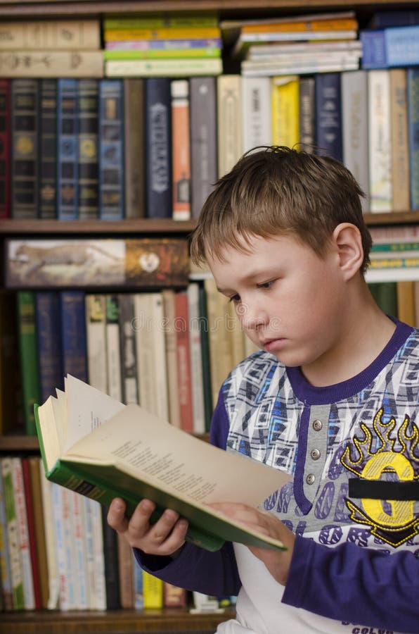 Thoughtful Little Boy Reading Book in the Library Stock Image - Image ...