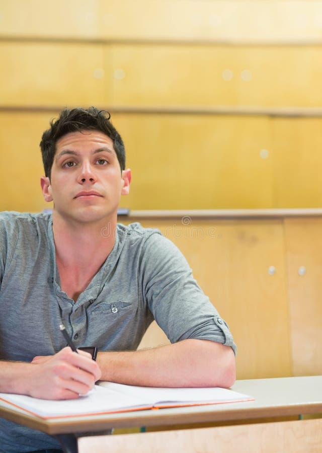 Male Student Leaning Forward Holding Pen Over Open Notebook at Lecture ...