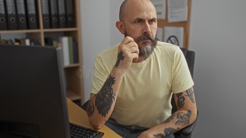 Thoughtful Man with Beard and Tattoos in an Office Setting, Sitting at ...