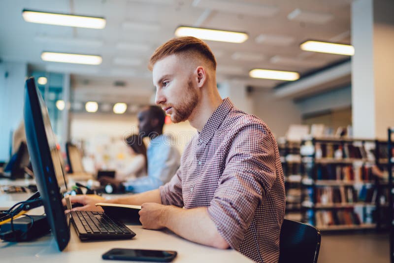 Thoughtful Mates Browsing Computers in Modern Library Stock Image ...