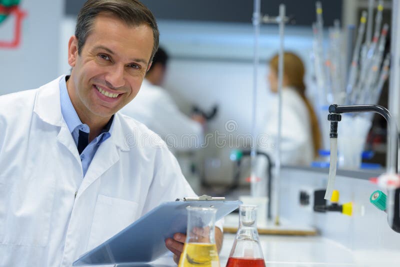 Thoughtful Technician in Lab Coat with Clipboard Stock Photo - Image of ...